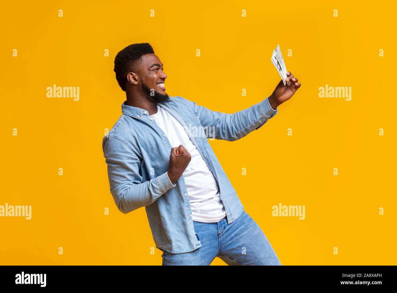 Happy black guy holding dollar cash celebrating success Stock Photo - Alamy