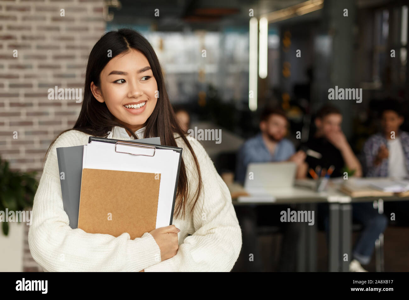 Female student posing in front of classmates in library interior Stock ...