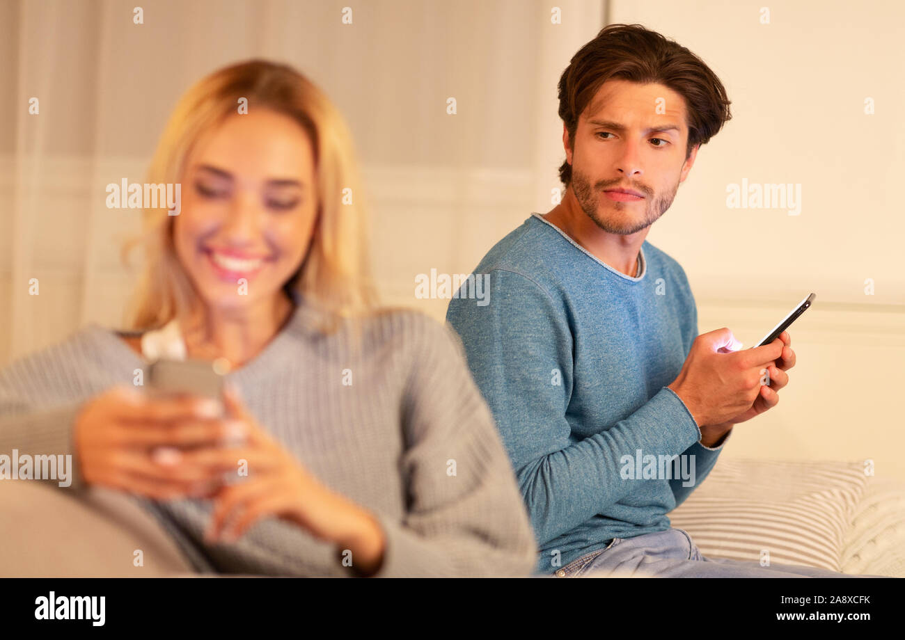 Suspicious Man Watching Girlfriend Texting On Phone Sitting At Home ...