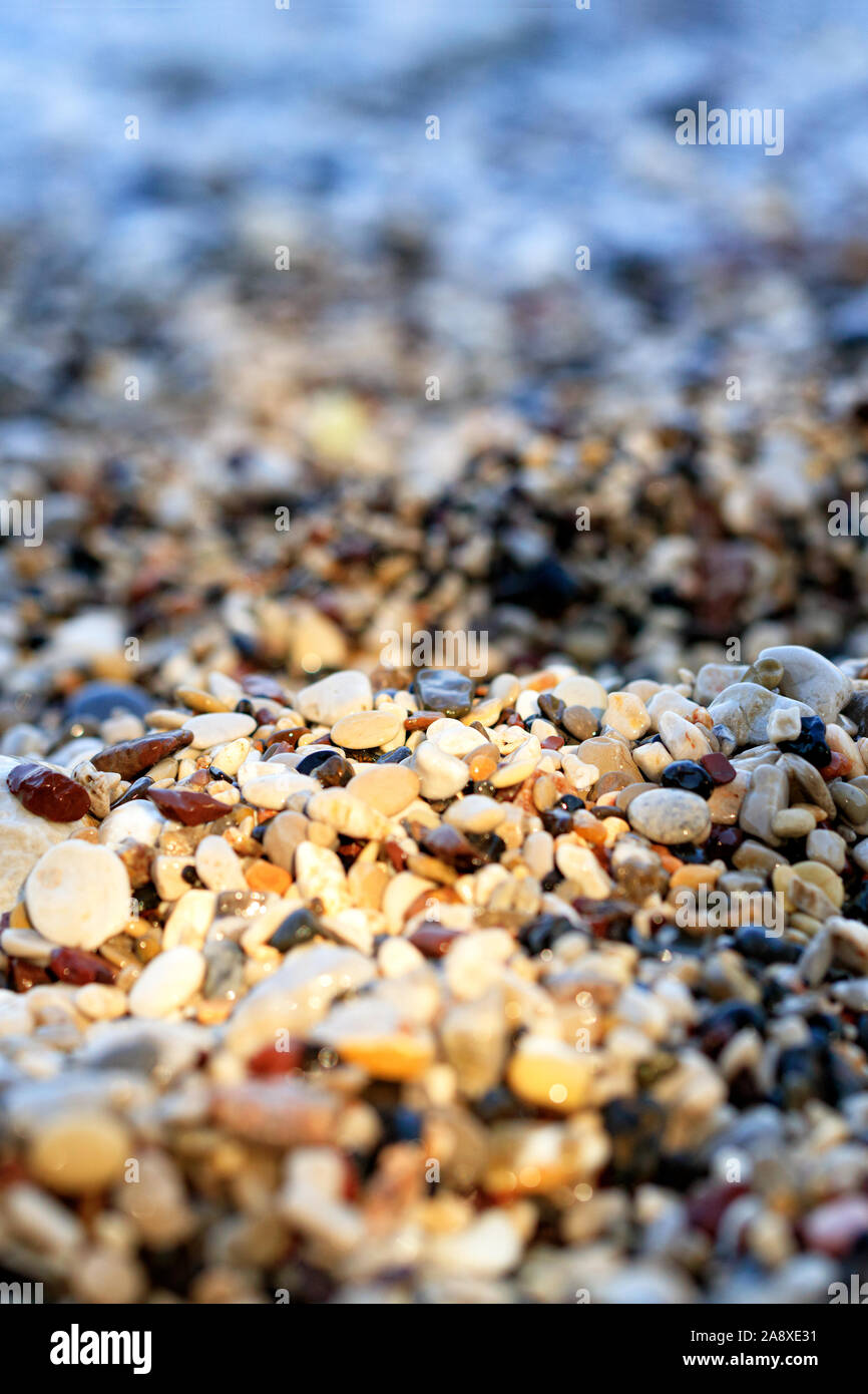 Pebble beach on the sea coast is illuminated by a narrow sunbeam and ...