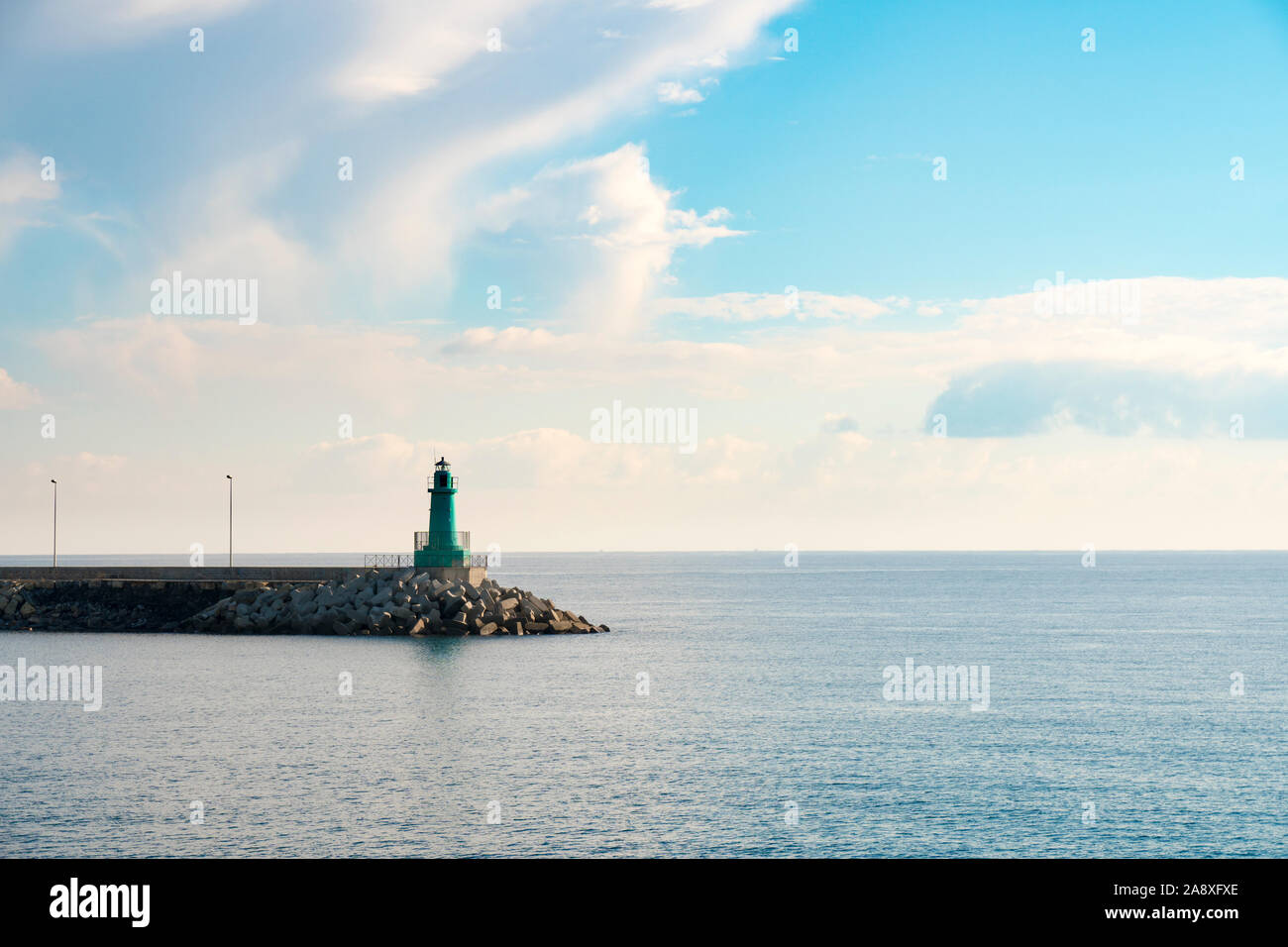 Small green lighthouse at the entrance of a port Stock Photo - Alamy