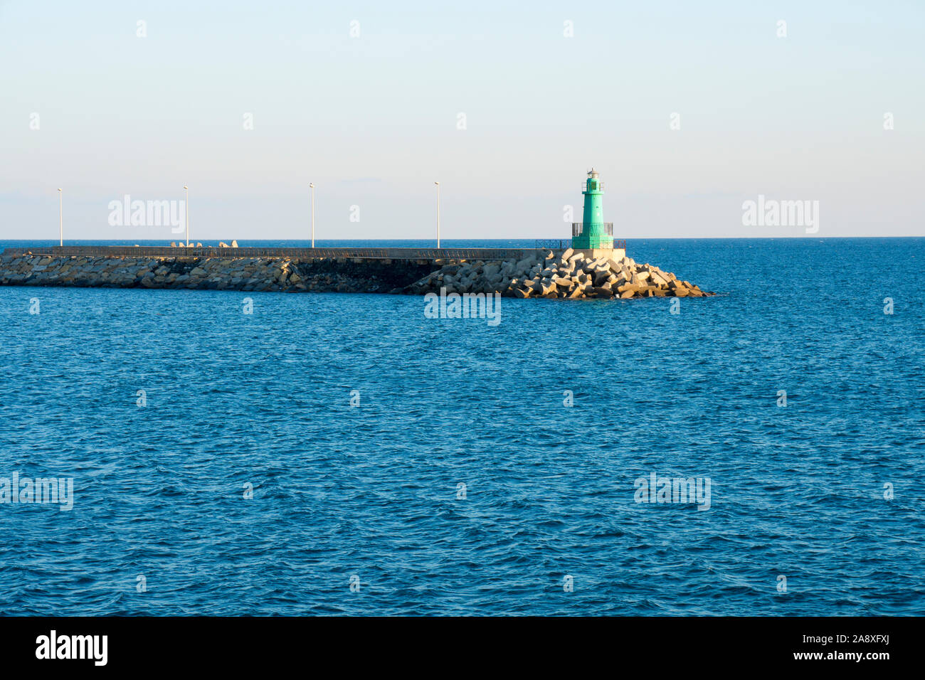 Small green lighthouse at the entrance of a port Stock Photo - Alamy