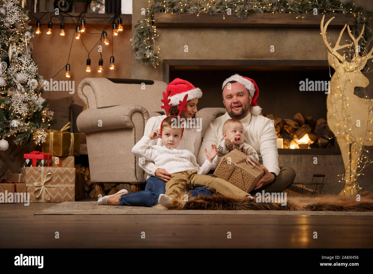 Image of parents with son at fireplace, deer with garland in room with ...