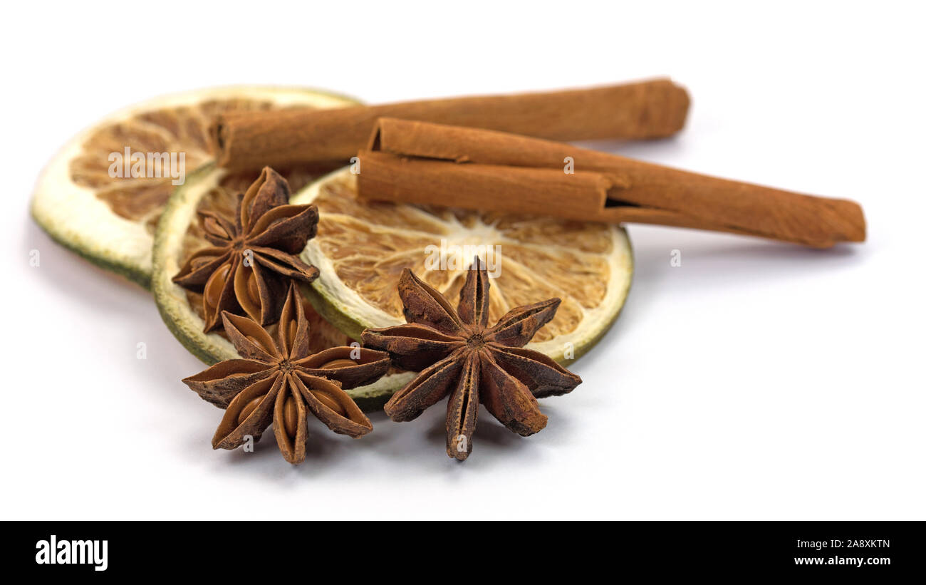 Anise stars, lemon slices and cinnamon sticks against white background ...
