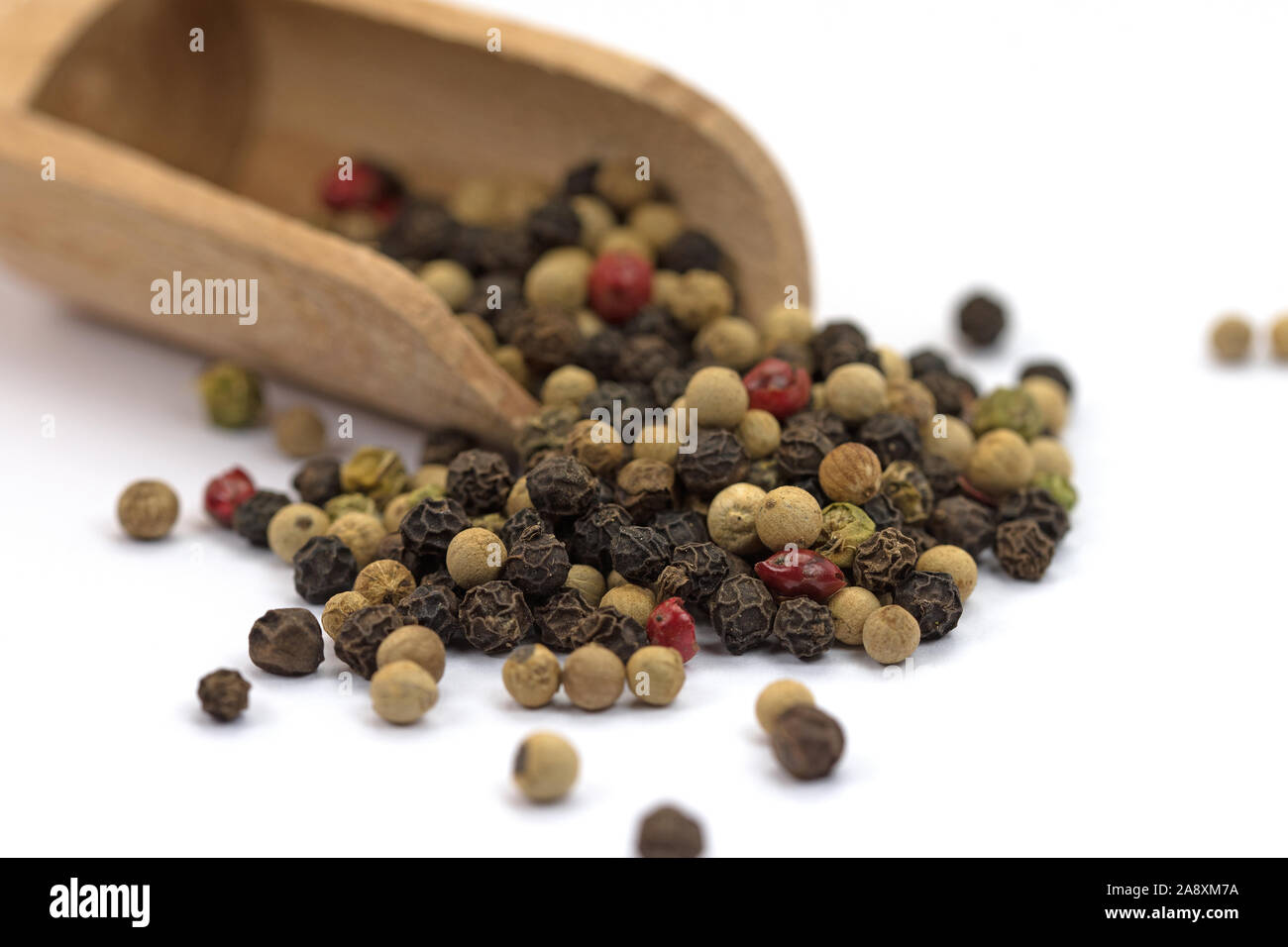 Colorful peppercorns on a spice scoop in front of white background ...