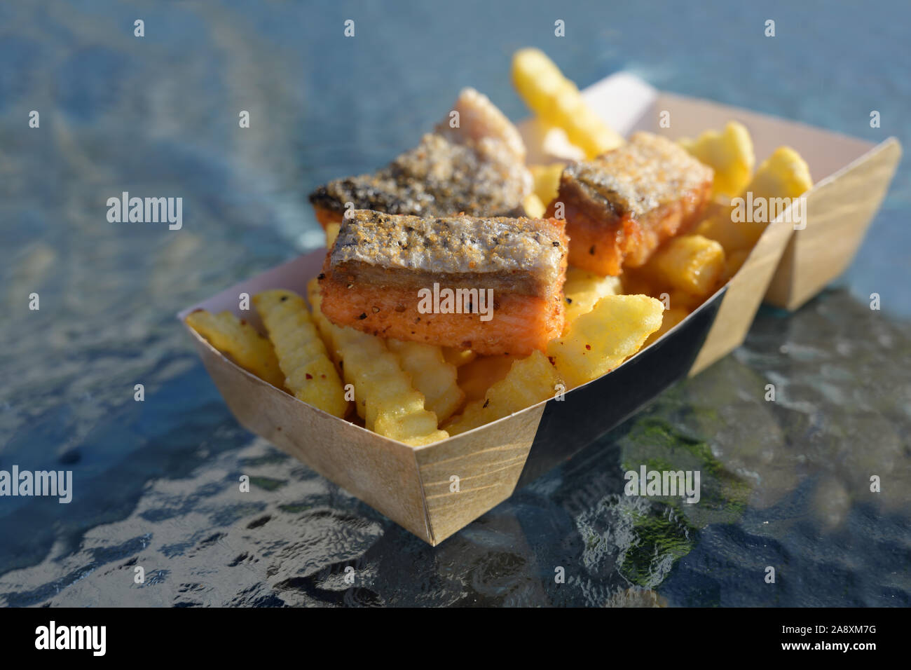 fish and chips with fried smoked salmon and french fries in a cardboard ...