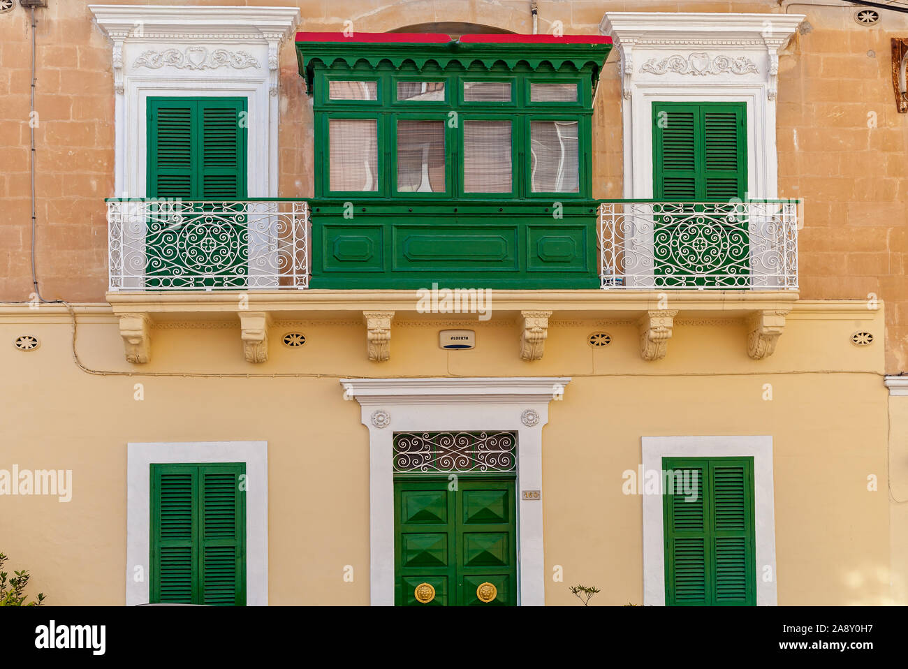 Malta architecture, facade of a house with wooden windows and a green ...
