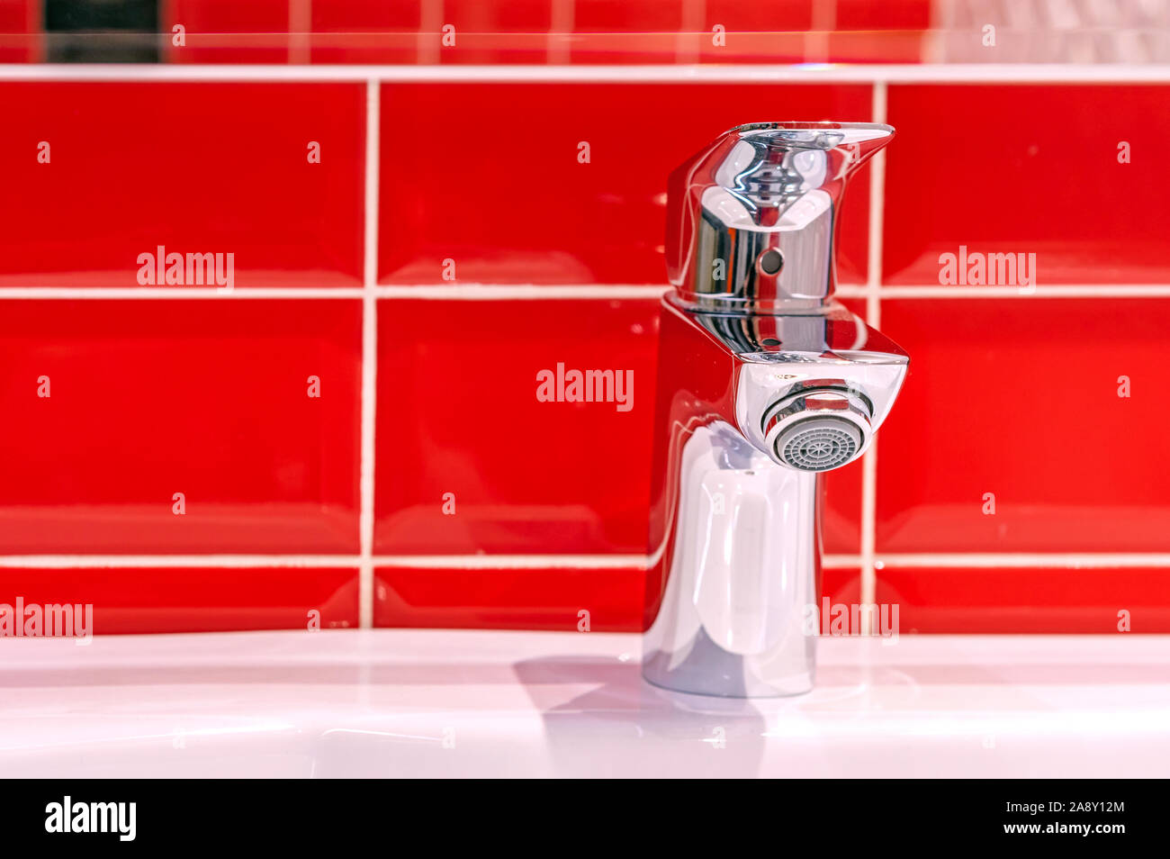 Chrome water tap on a red ceramic tile background Stock Photo - Alamy