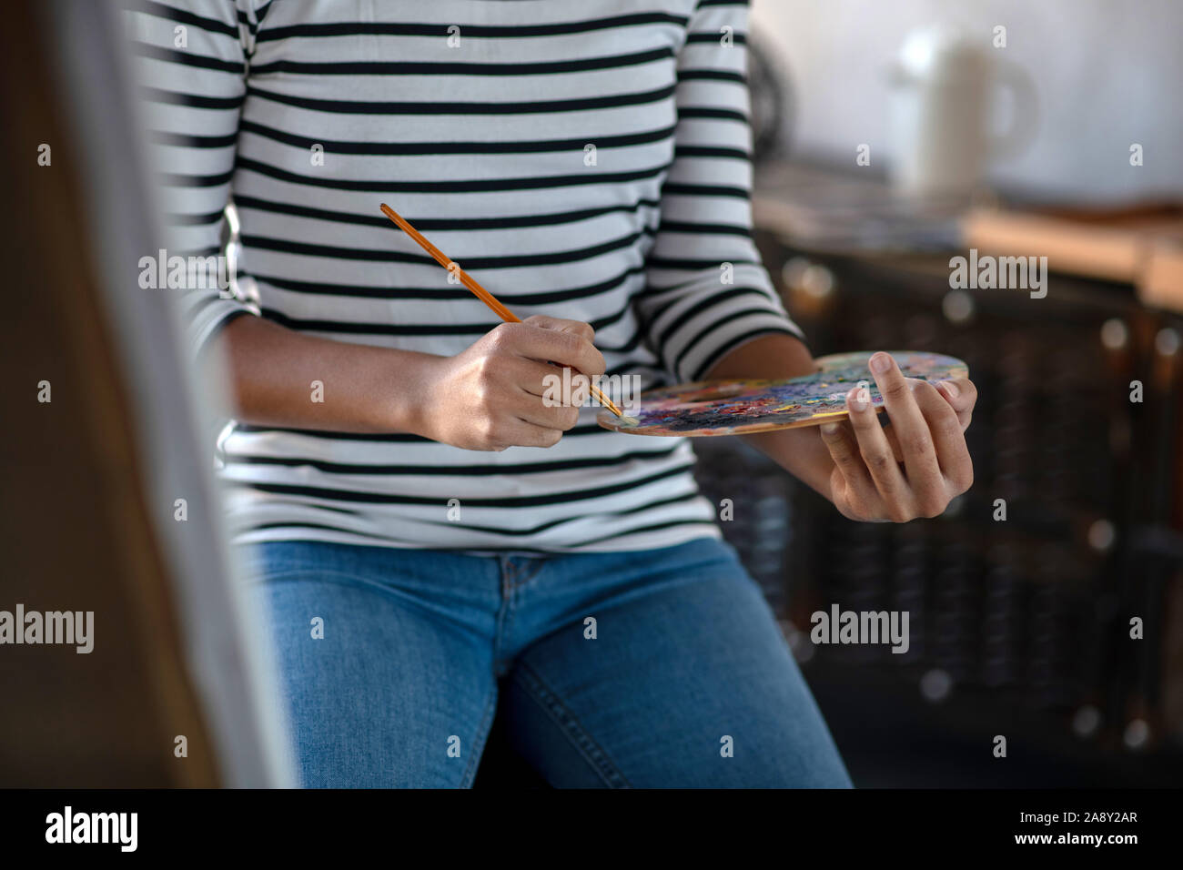 Close up of artist wearing jeans mixing colors of paints Stock Photo ...