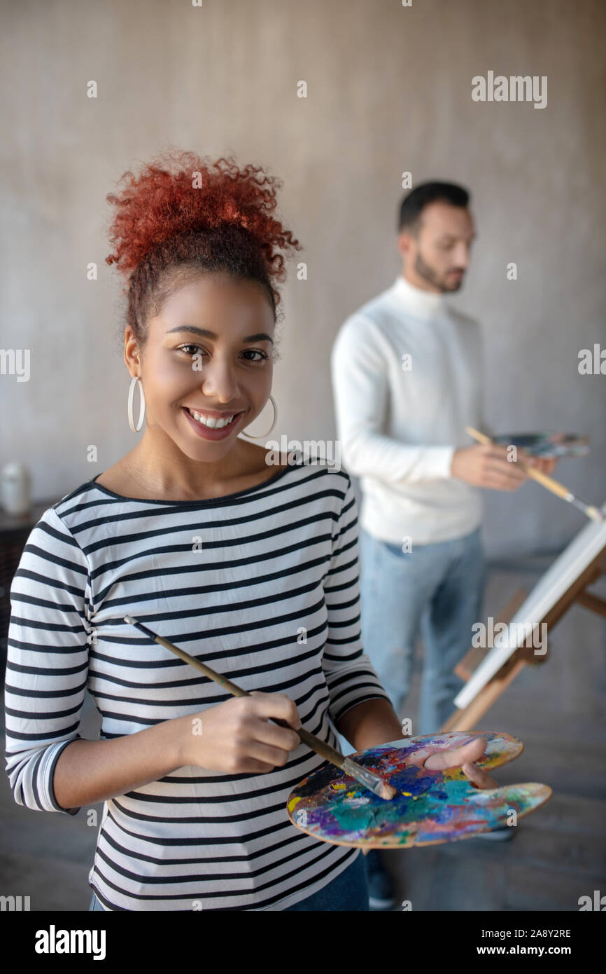 Appealing artist wearing striped shirt mixing gouache Stock Photo - Alamy
