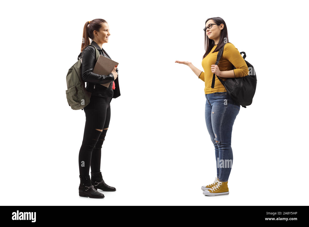 Full length profile shot of two female friends standing and talking ...