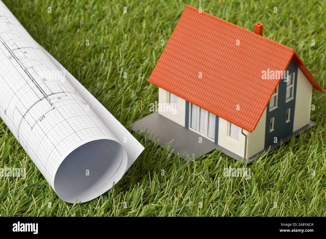 Miniature house model with architectural blueprint on green grass lawn ...