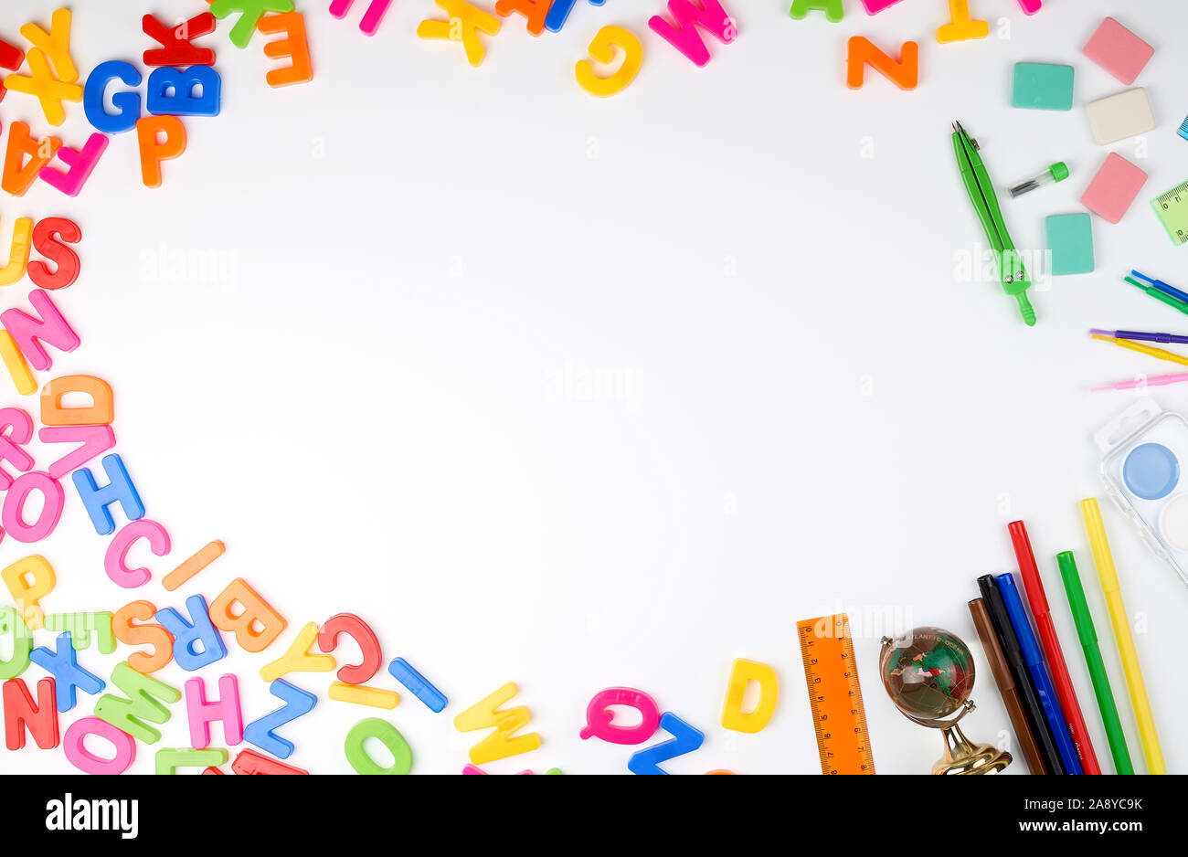multicolored English alphabet letters and school supplieson a white ...