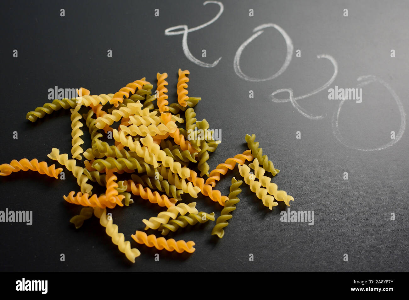 Uncooked fusilli over black background with number 2020 from above ...