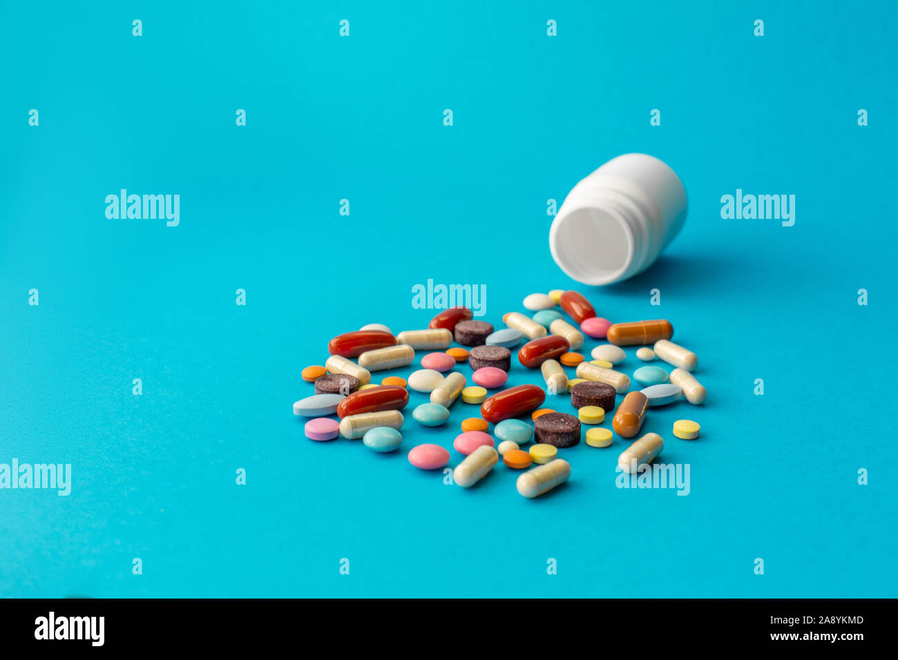 A handful of colored pills spilled out of the can on a blue background ...