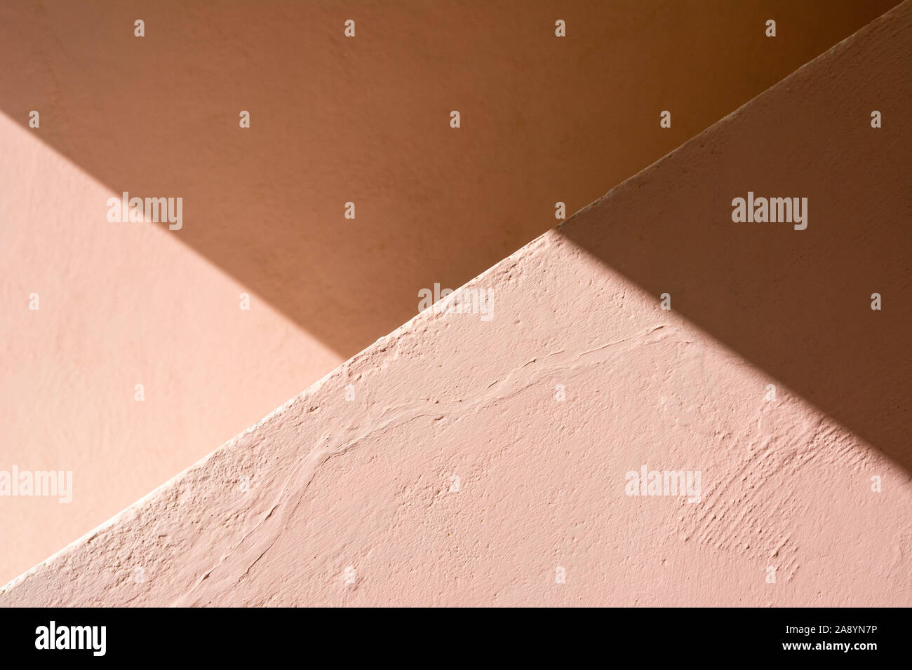 Abstract - terra cotta coloured walls in midday sun with shadows making ...