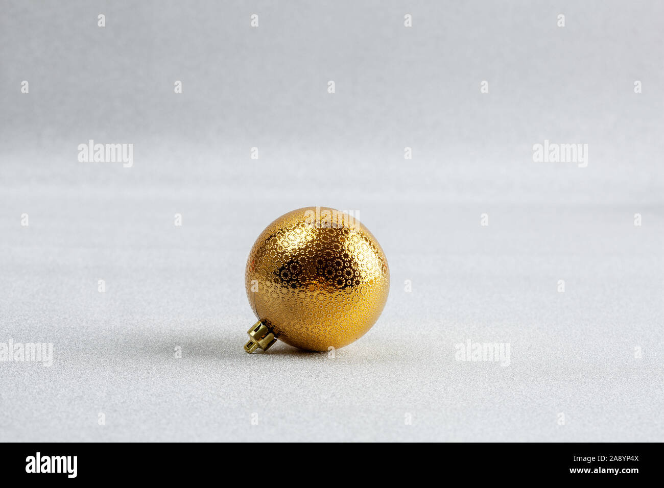 Golden Christmas bauble on silver glitter background with copy space ...