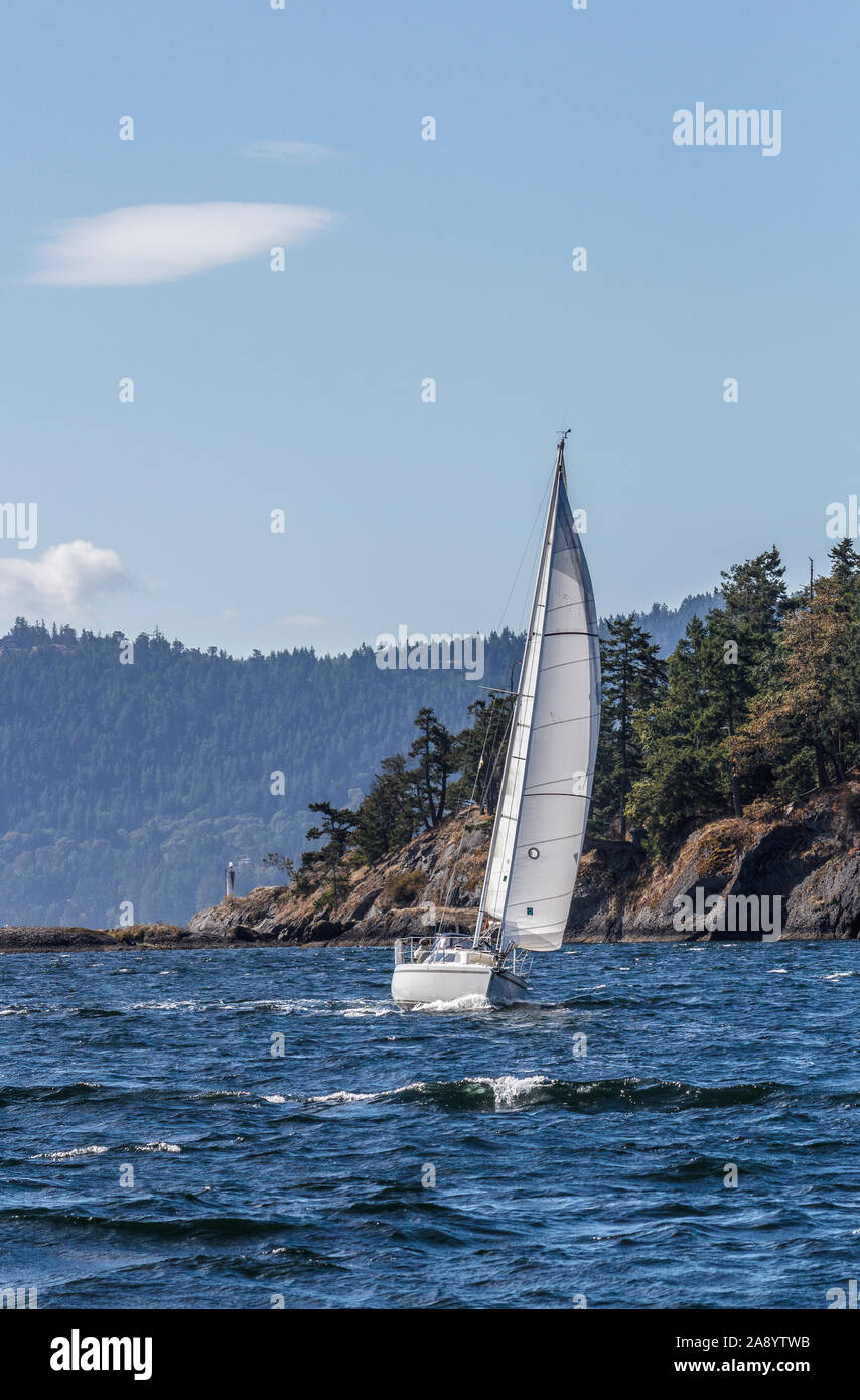 Under clear skies and amid breaking waves, a man sails a boat on a beam ...