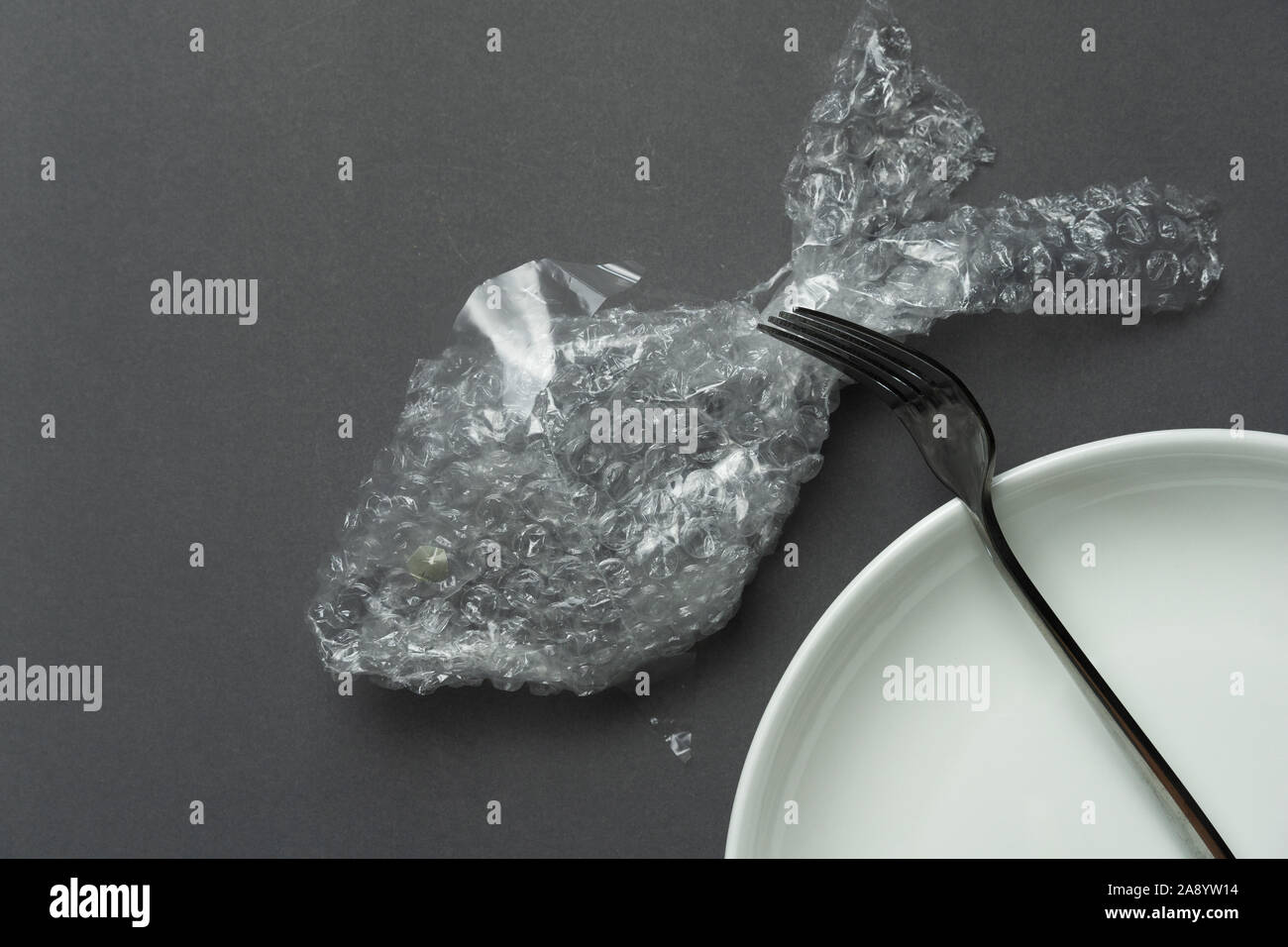 garbage plastic fish model with metal fork and dish for eating food in ...