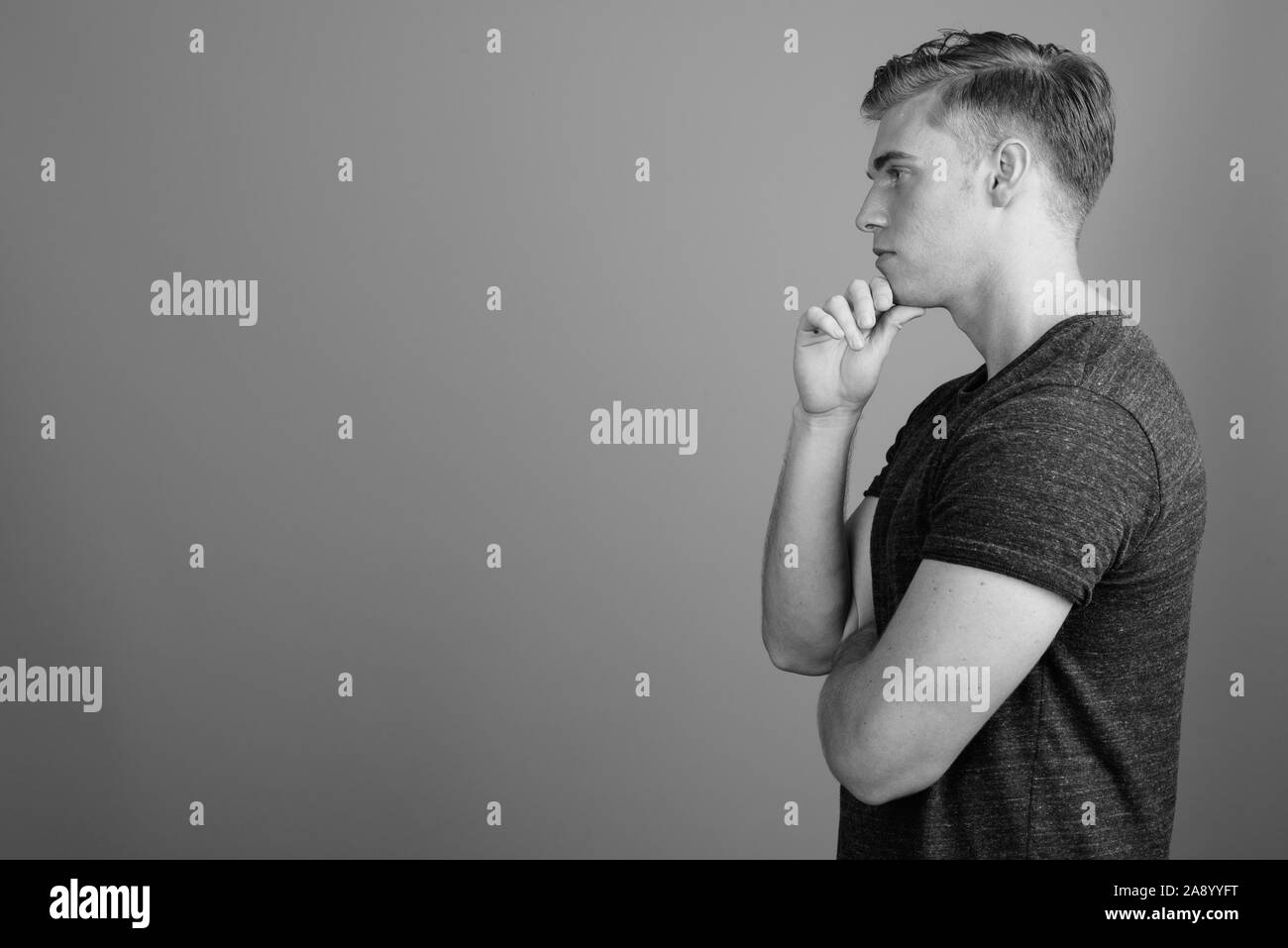 Profile view of young handsome man against gray background in black and ...
