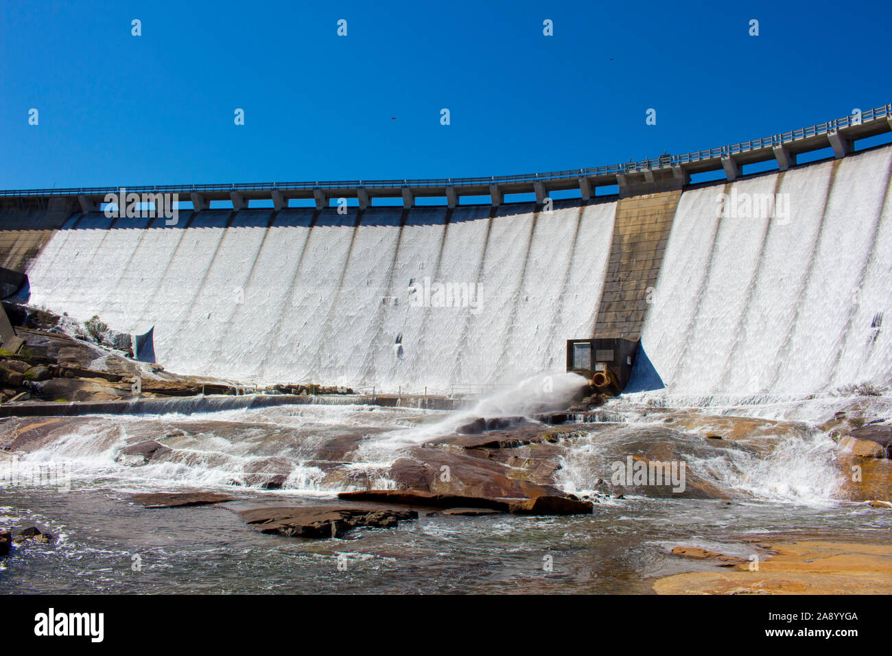 Water streaming and overflowing over the massive concrete wall and ...