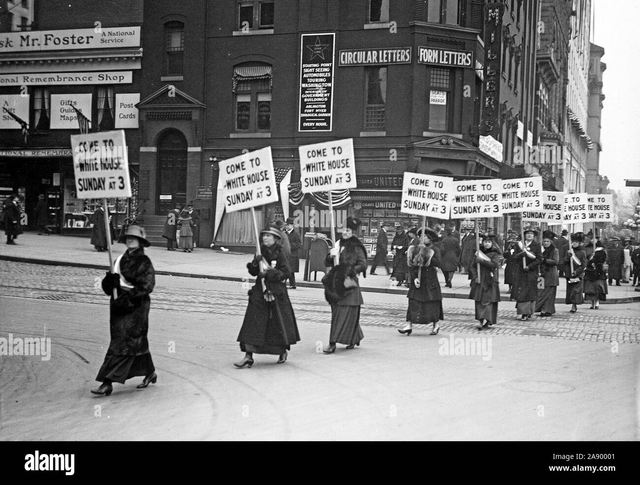 Woman suffragettes marching through the streets carrying signs inviting ...