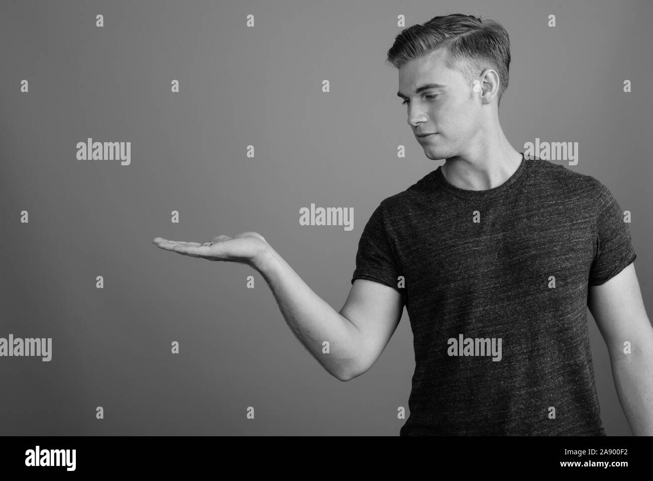 Profile view of young handsome man against gray background in black and ...