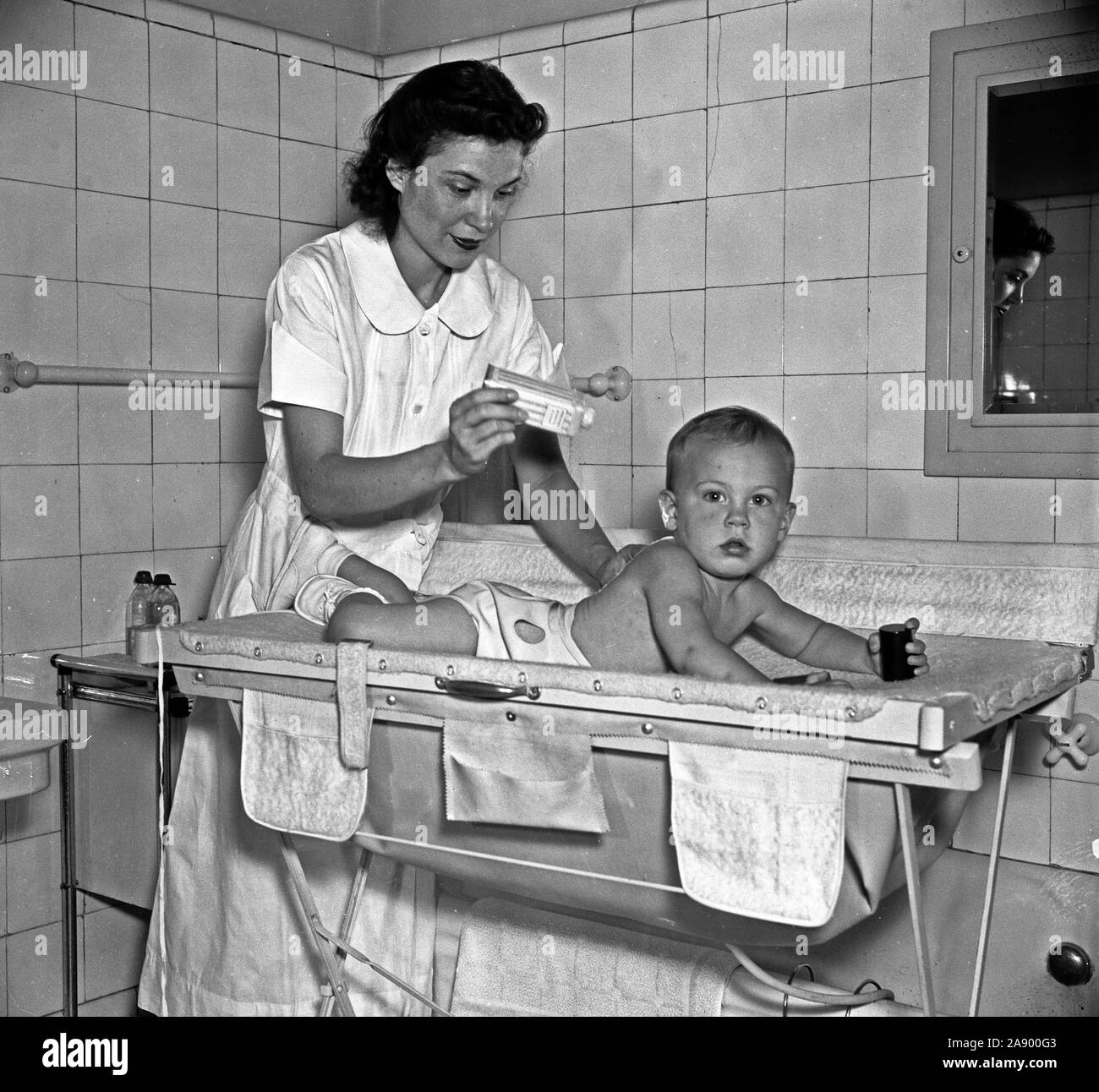 Baby being given a bath ca. 1937-1939 Woman putting baby powder on baby ...