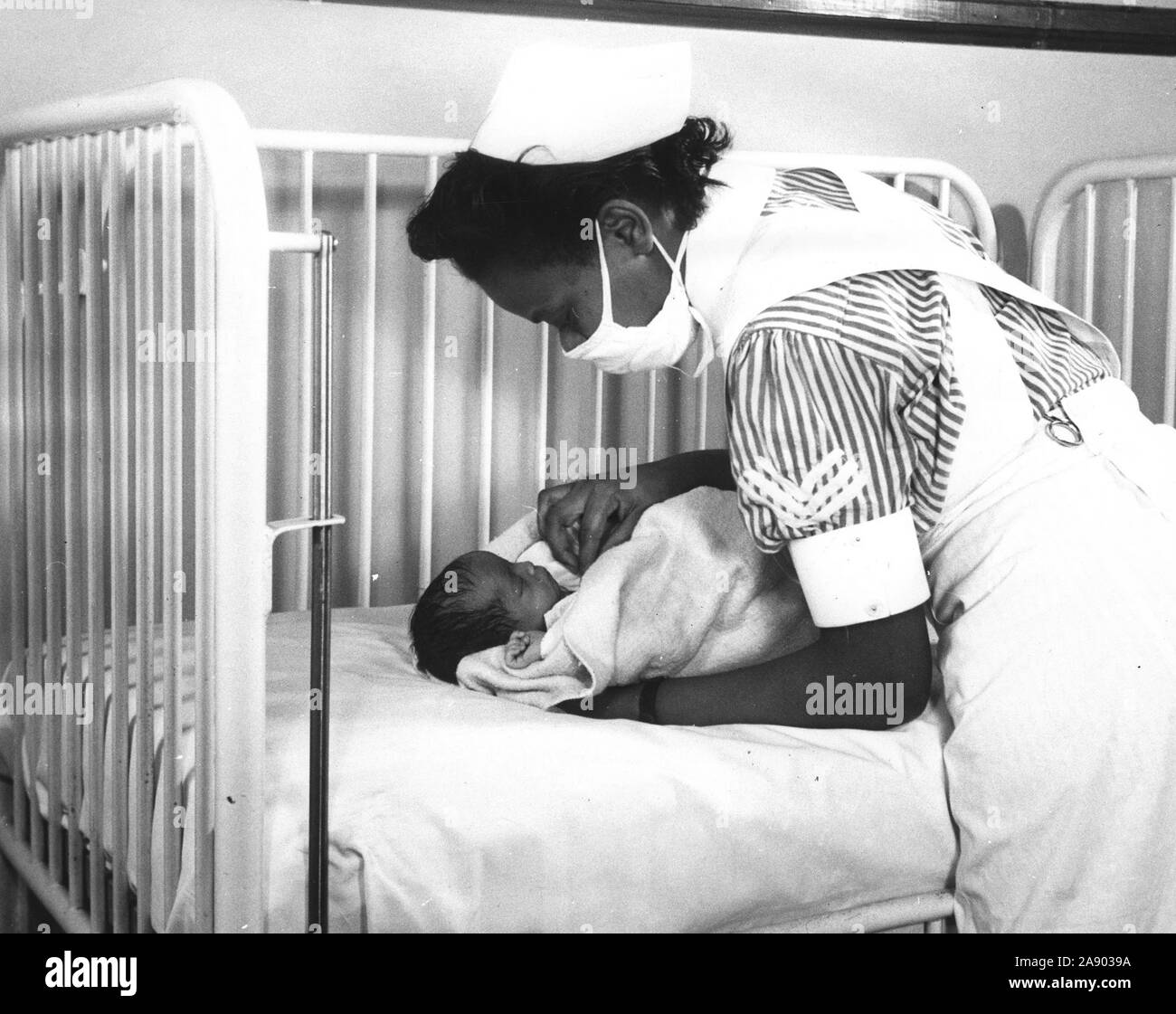 A nurse is leaning over a newborn in a crib Stock Photo - Alamy