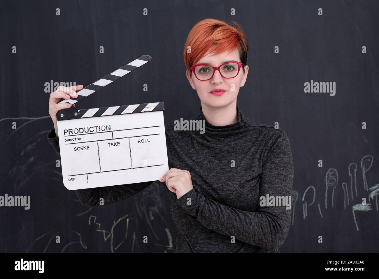 redhead woman on black chalkboard holding movie clapper cinema concept ...