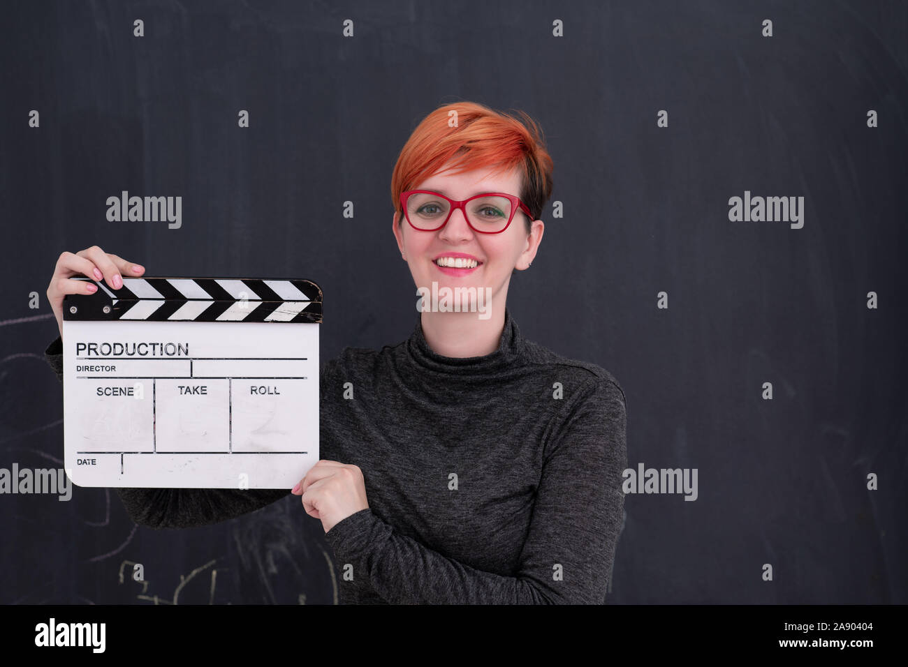 redhead woman on black chalkboard holding movie clapper cinema concept ...