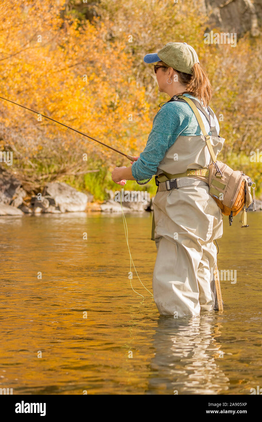 A woman strips her line through her fly rod and reel while fishing ...