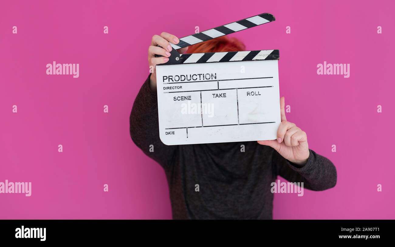 redhead woman holding movie clapper isolated against pink background ...