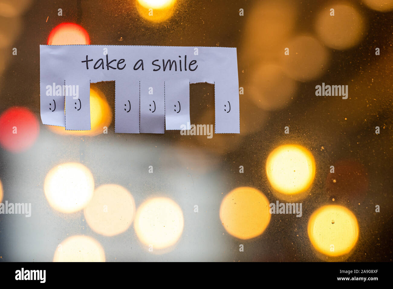 window with paper with the phrase: Take A Smile and with a smile symbol ...