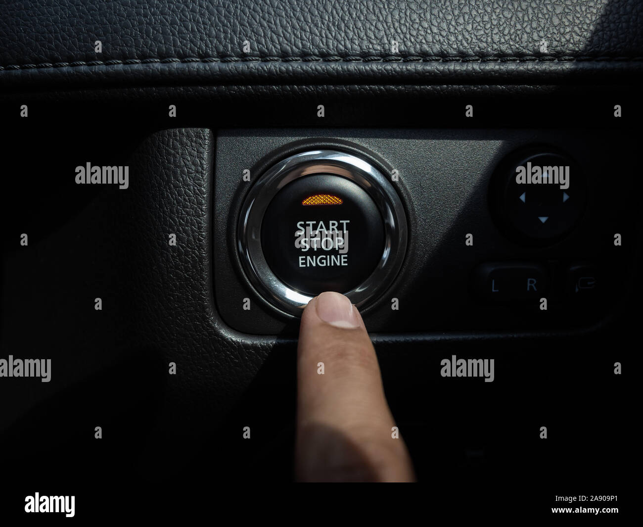 Finger push on Start-Stop engine button with orange light on black car ...