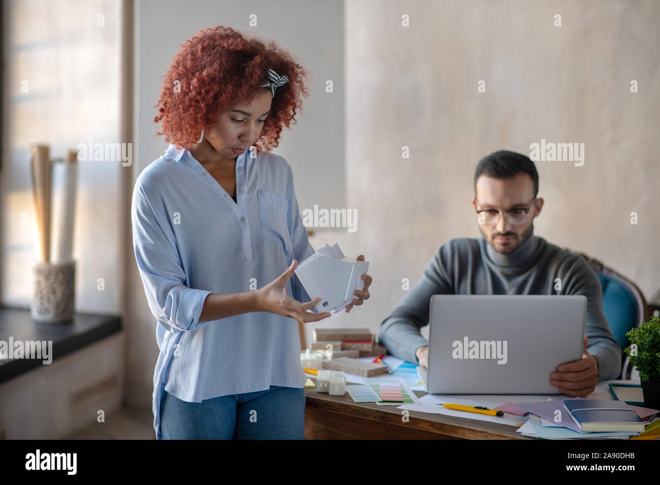 Curly interior designer holding white house model Stock Photo - Alamy