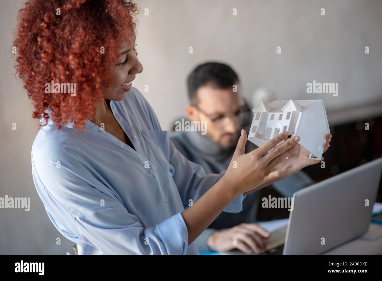 Designer holding house model while standing near colleague Stock Photo ...