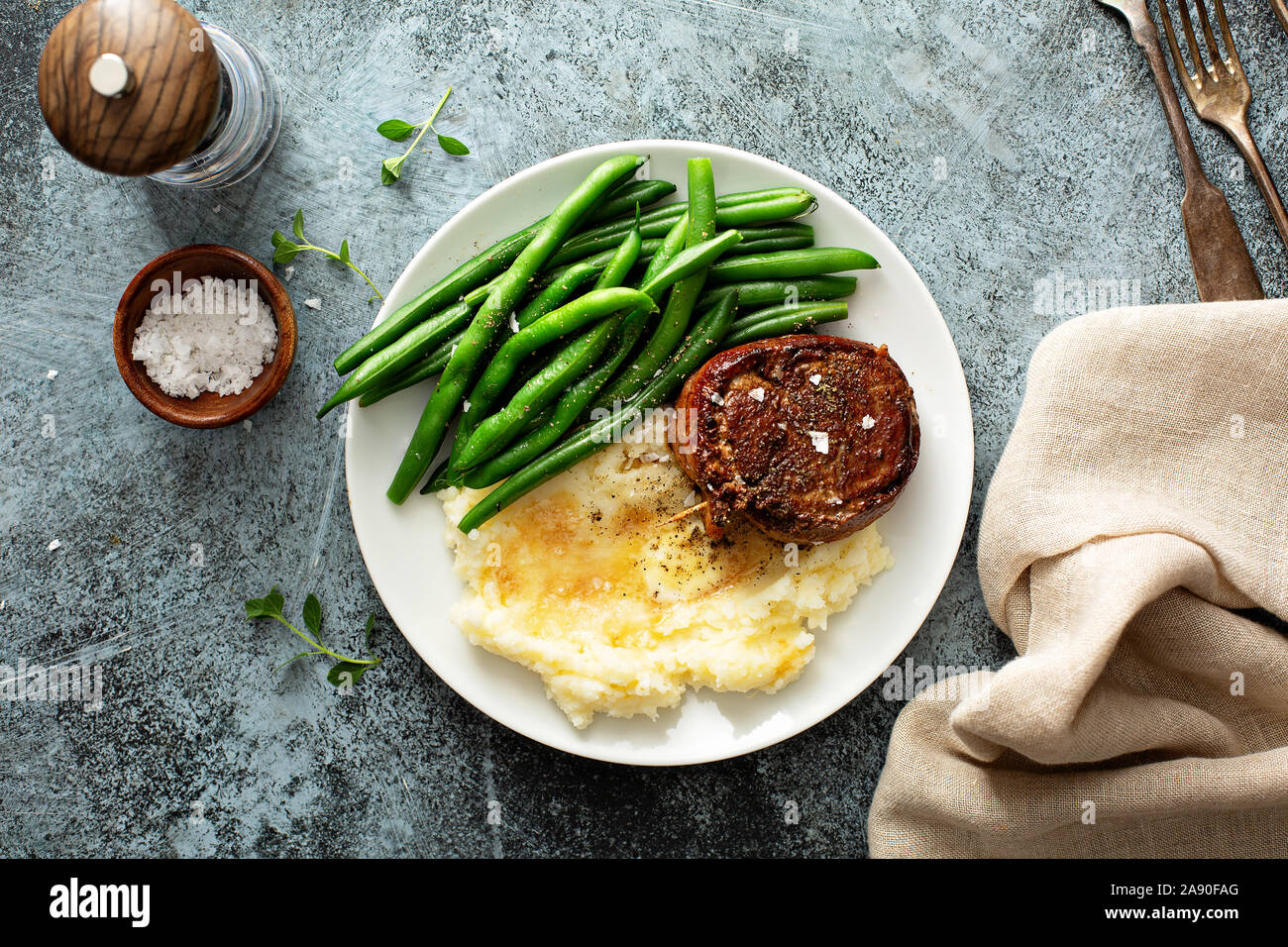 Traditional dinner meal with a bacon wrapped steak, green beans and ...