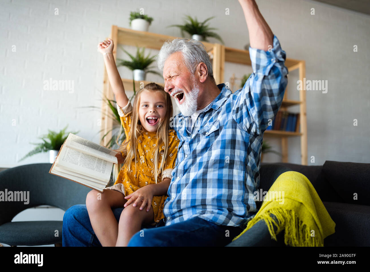 Bearded grandfather and his grandchild are having fun reading a book ...