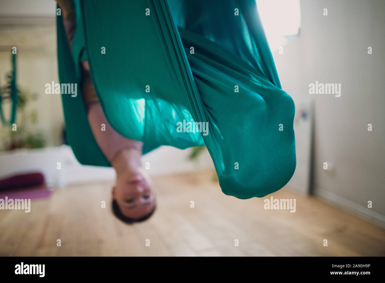 Aerial antigravity yoga concept. Woman practicing fly yoga in anti-gravity yoga studio using ...