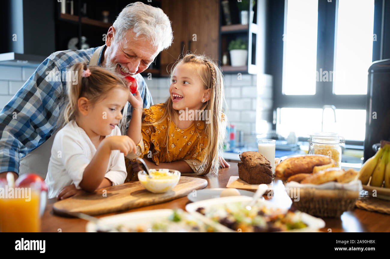 Smiling grandfather helping children to cook in the kitchen Stock Photo ...