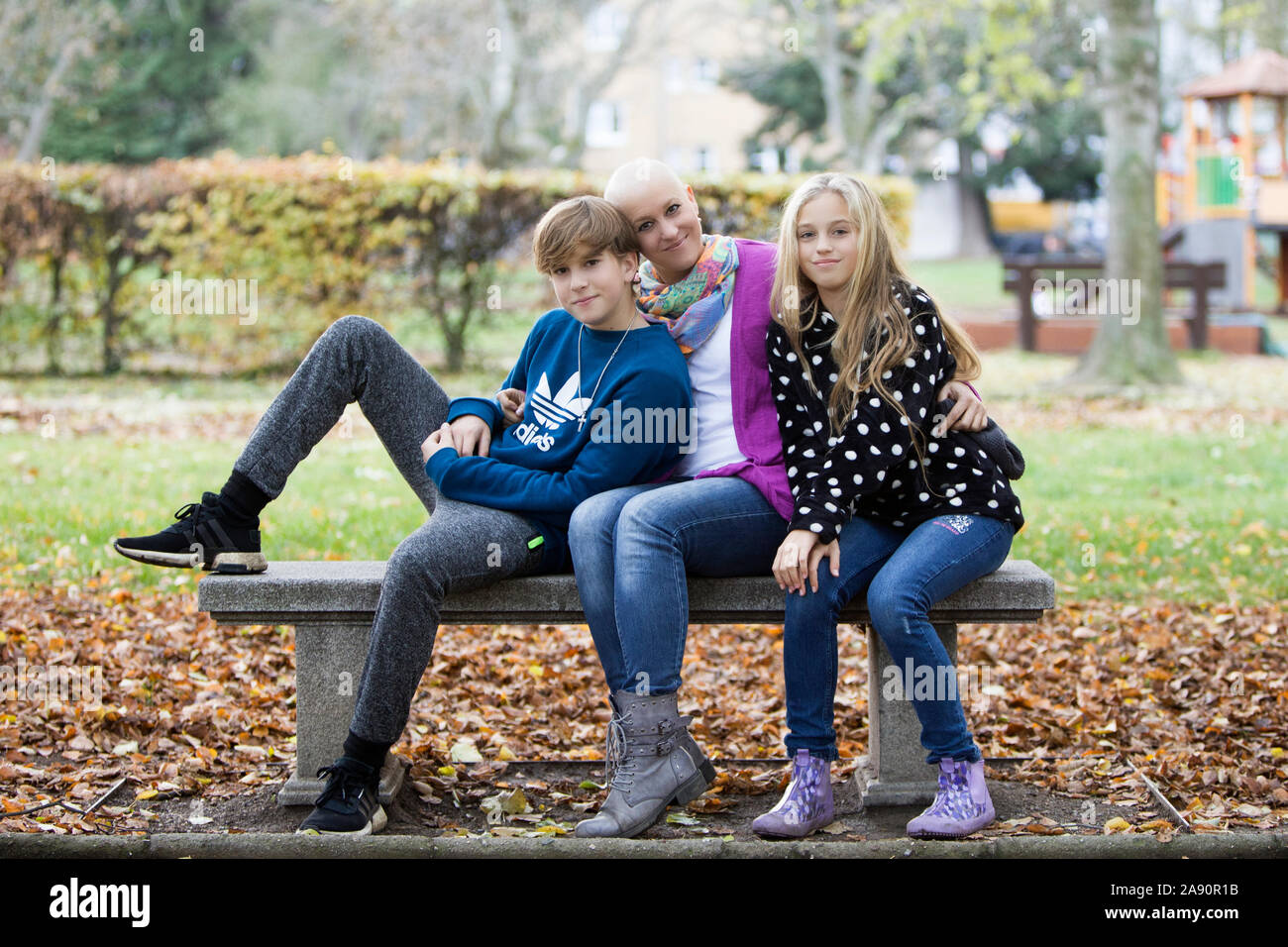 Mother on cancer treatment posing with her kids in colorful autumn park ...