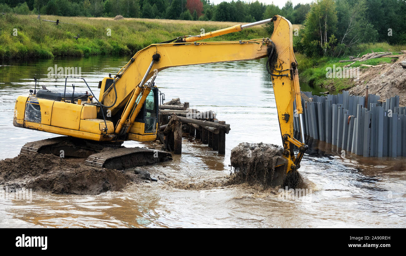 Excavator working in the small forest river, excavator bucket ...
