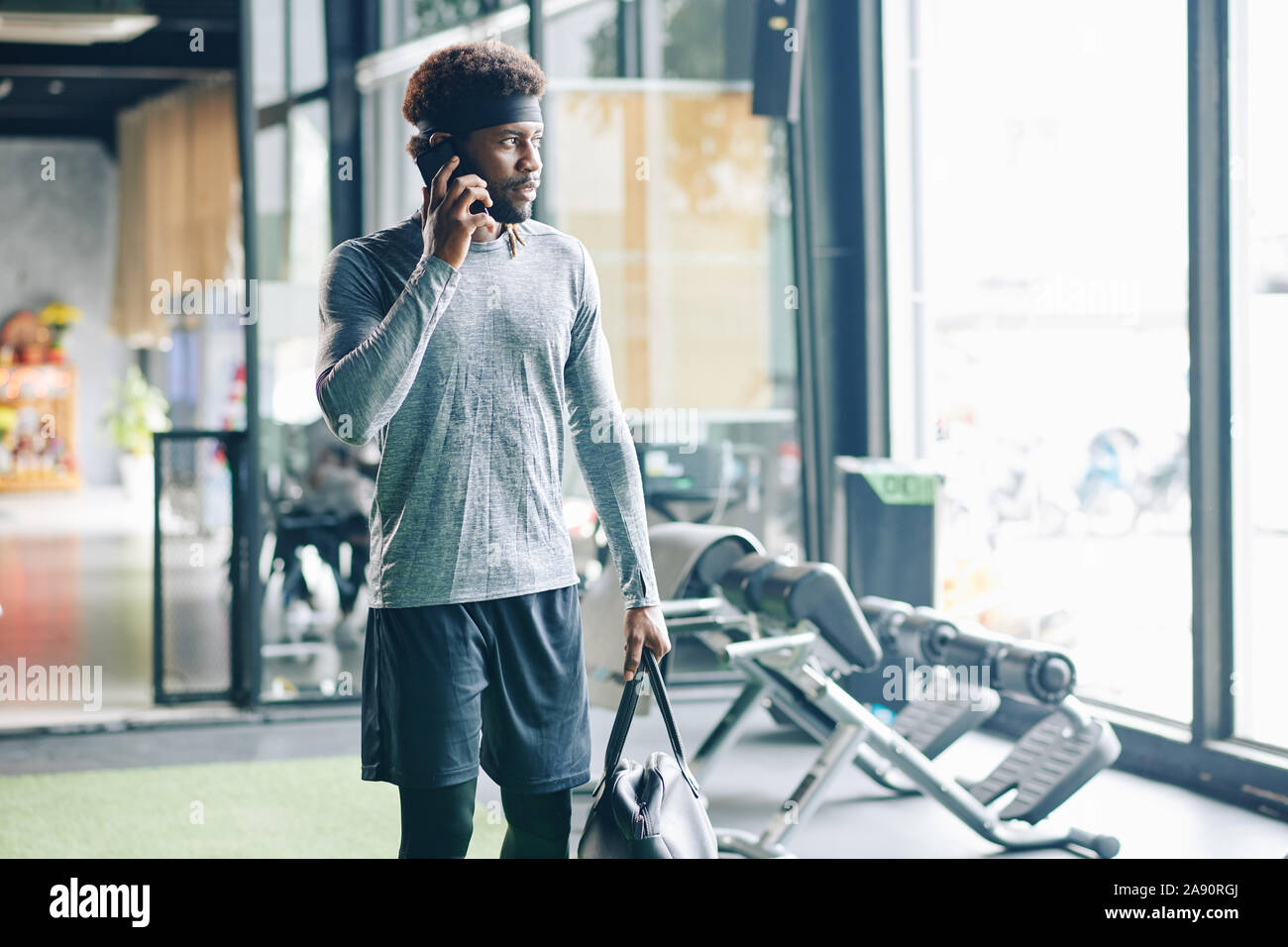 Fit Black young man talking on phone when coming to gym in the morning ...