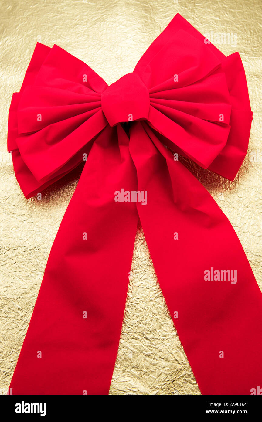 Large festive red bow decorating shiny textured gold wrapping paper ...