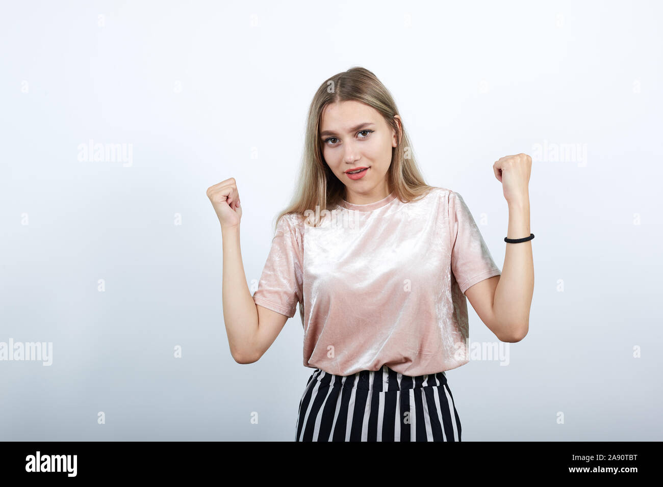 Young woman standing doing winner gesture with arms raised, smiling for ...