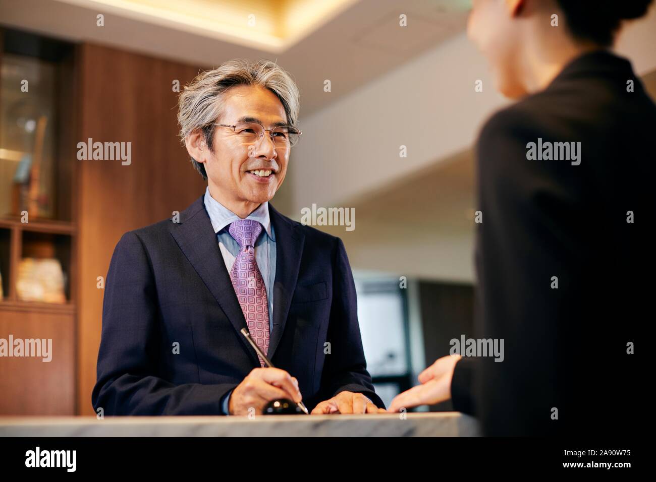 Senior businessman checking in at hotel Stock Photo - Alamy