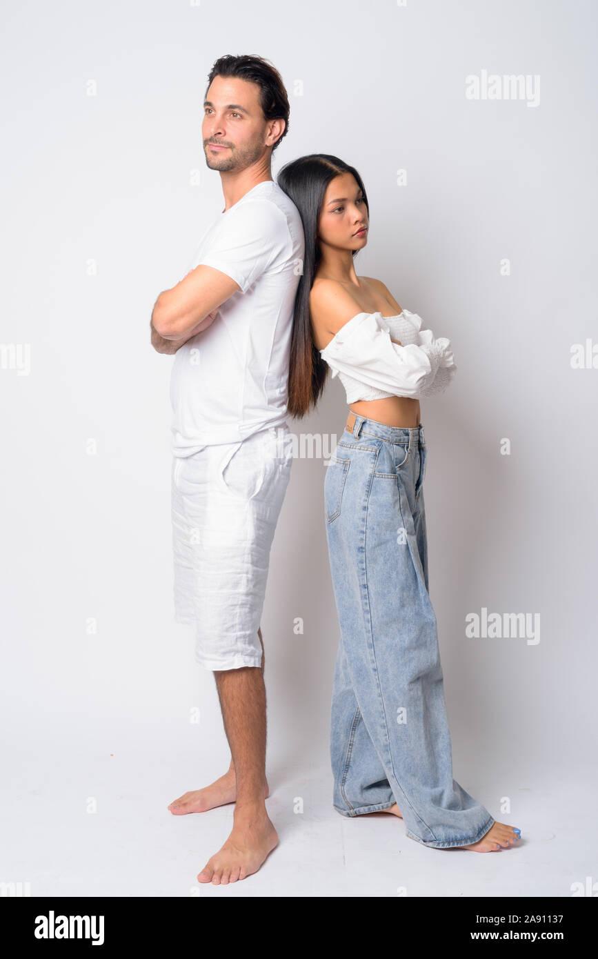 Full body shot of multi ethnic couple thinking together with arms ...