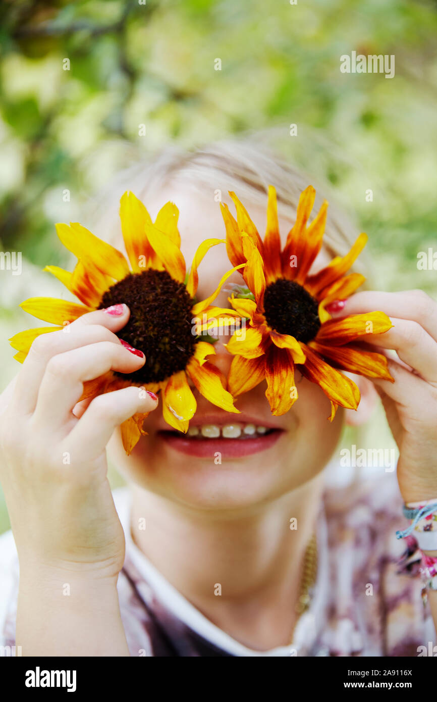 Girl holding flowers in front of her face Stock Photo - Alamy