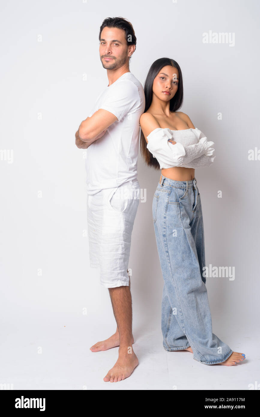 Full body shot of multi ethnic couple together with arms crossed back ...